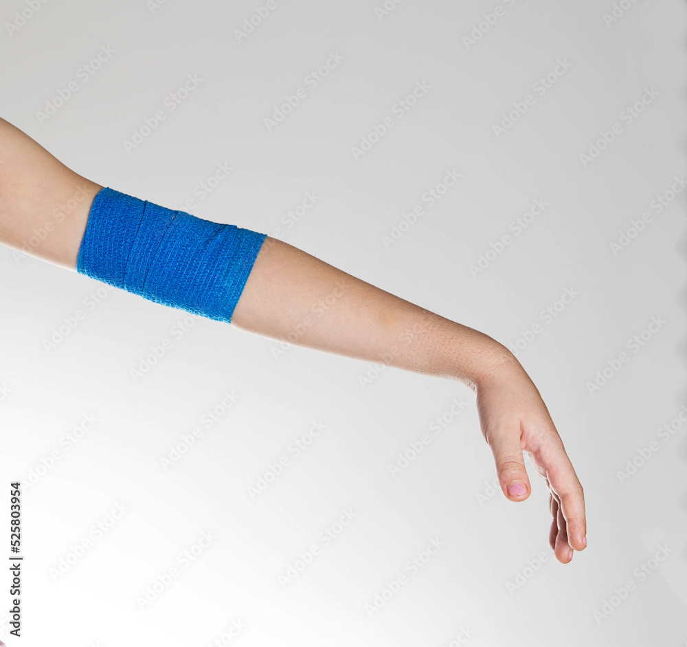 Blue elastic bandage on the elbow joint of the child on the arm. White ...