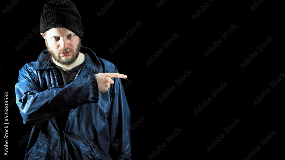 Bearded homeless points to empty space on black background, copy space ...