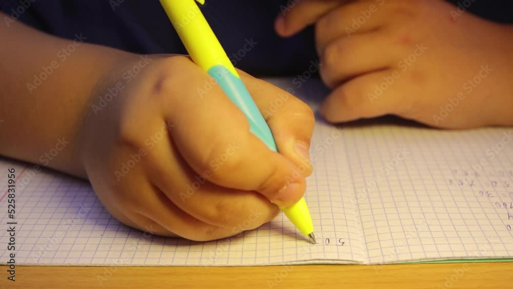 Close-up of a student's hands solving math examples in a notebook ...