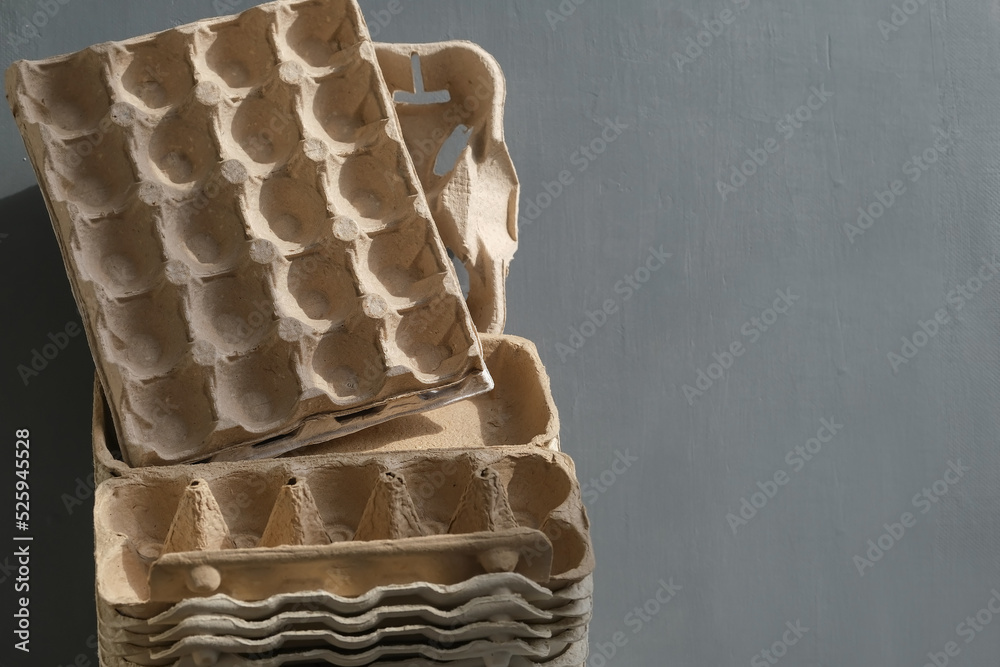 egg cardboards and empty egg carton boxes on a grey wall background ...