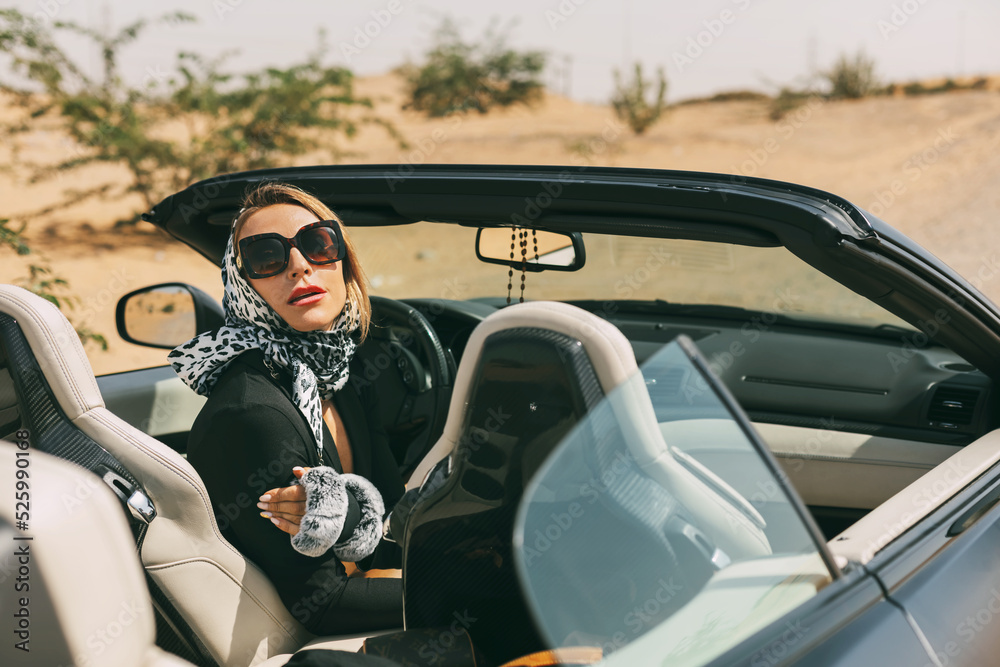 Glamorous blonde in a silk scarf and sunglasses in the driver's seat of ...