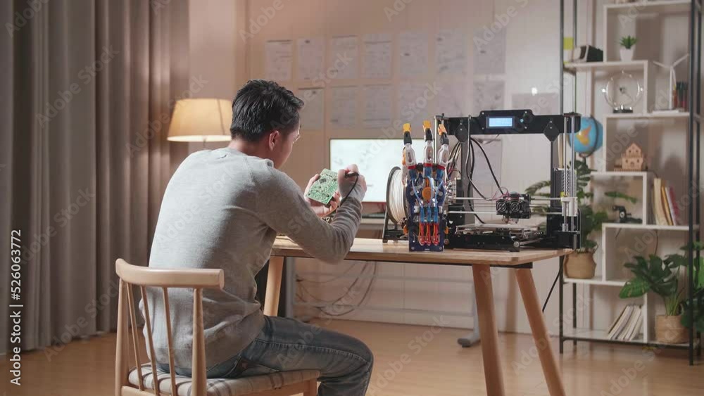 Back View Of Asian Male With 3D Printing Holding And Fixing The Board While Repairing A Cyborg ...