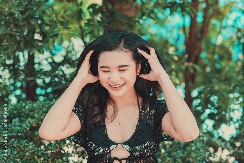 Happy, young and fair skinned woman lifts her hair up to feel cooler in ...