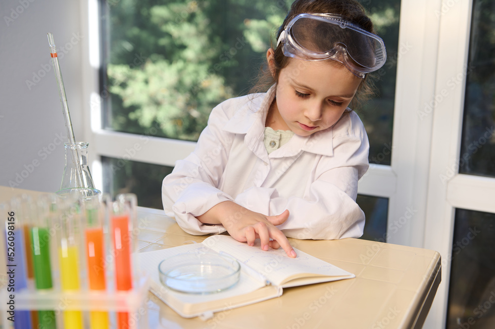 European smart little girl, future chemist in safety goggles and white ...