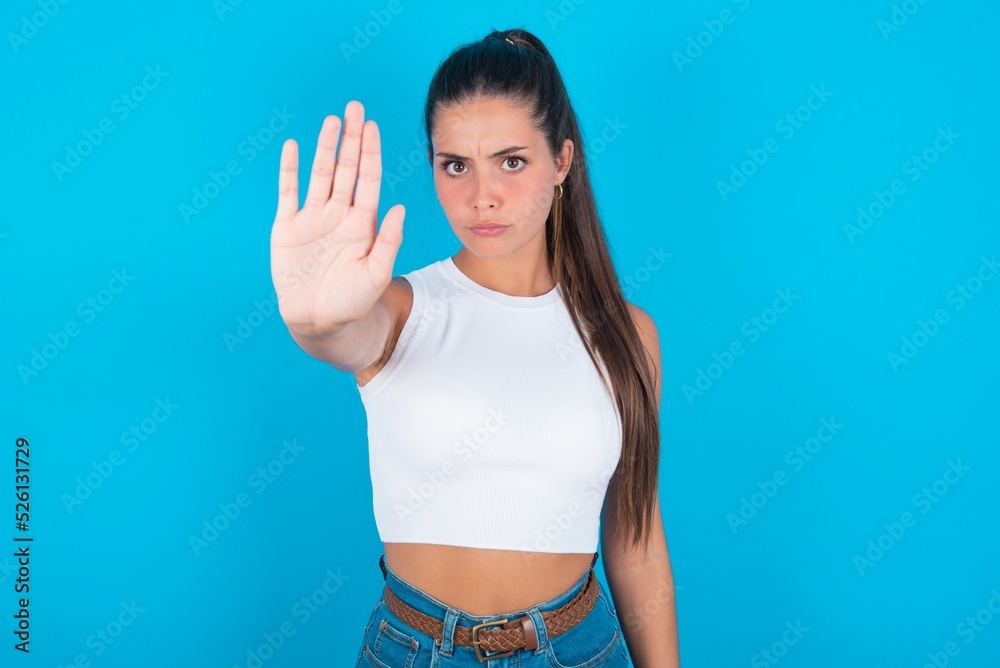 beautiful brunette woman wearing white tank top over blue background ...
