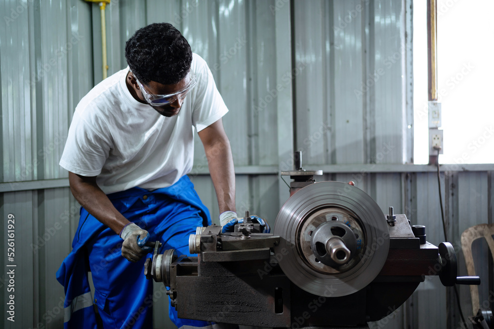 A black man African American worker working a steel cutter in an ...