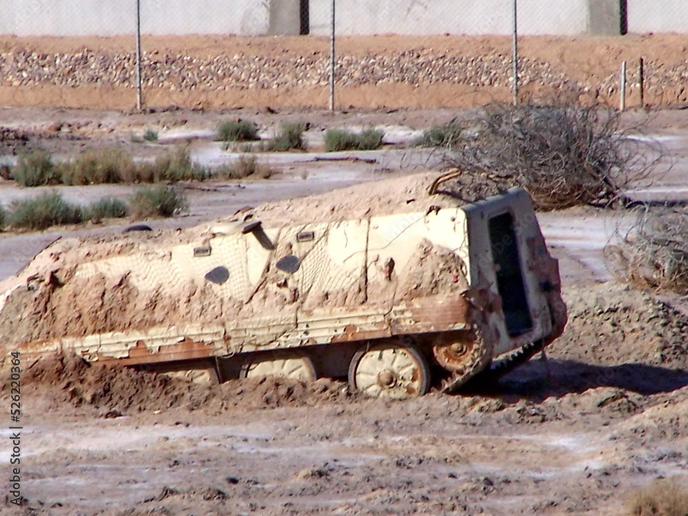 Ruins of an armored personnel carrier in the desert by an air station ...