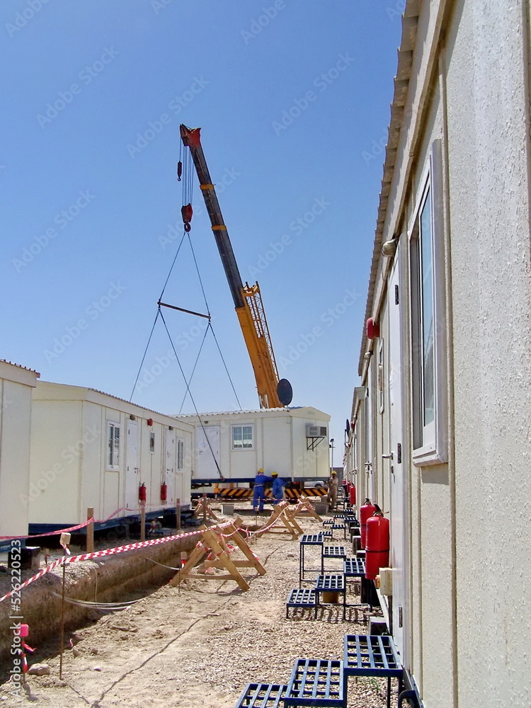 Crane placing containerized housing units on a camp at the air station ...