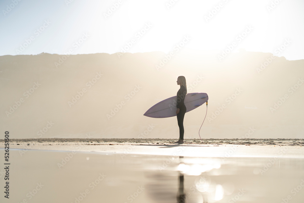 Beautiful surfer girl at the beach standing with her surfboard at ...