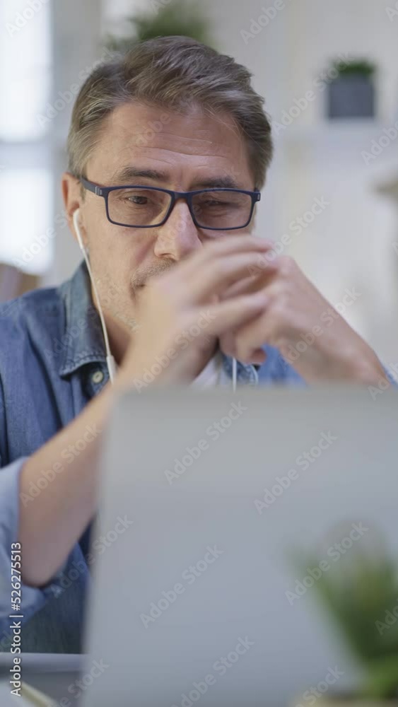 Portrait of middle aged man sitting at desk in bright room working with ...