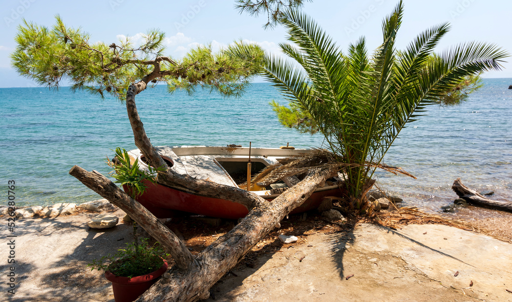 Weathered fishing boat lying on a rocky beach on Petalidi, Messinia ...