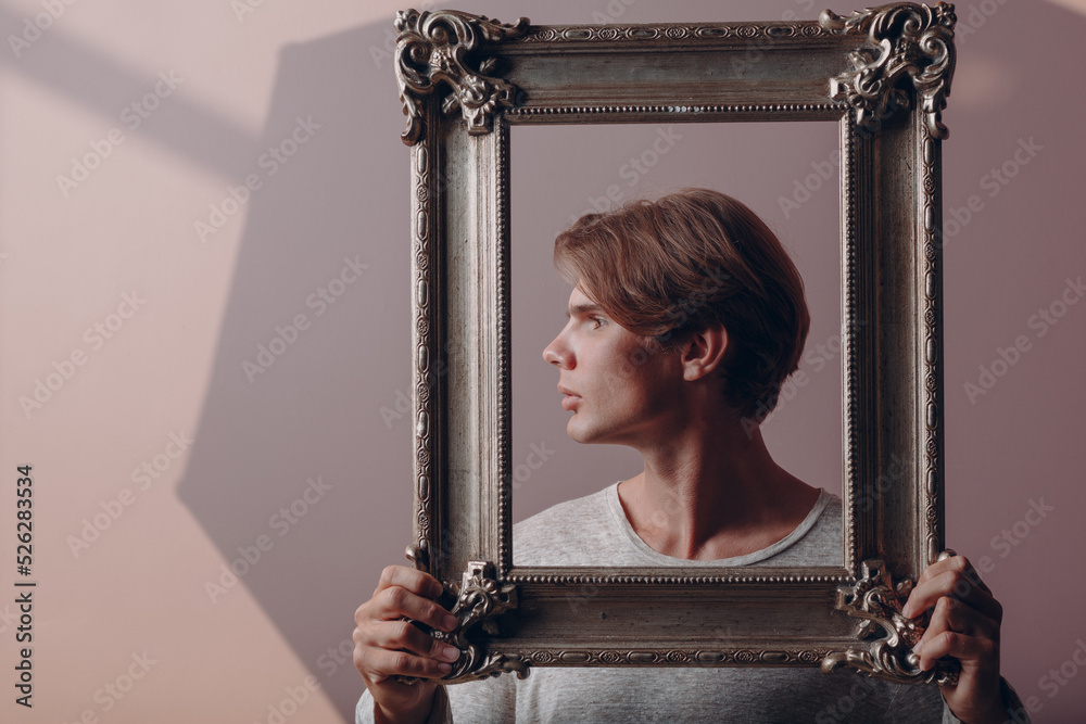 Millenial young man artist with blonde hair on gilded picture frame ...