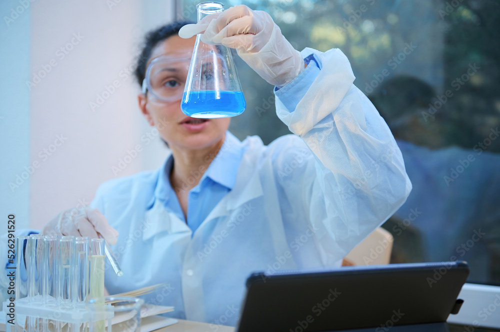 Selective focus on flat-bottomed flask in the hand of woman chemist ...