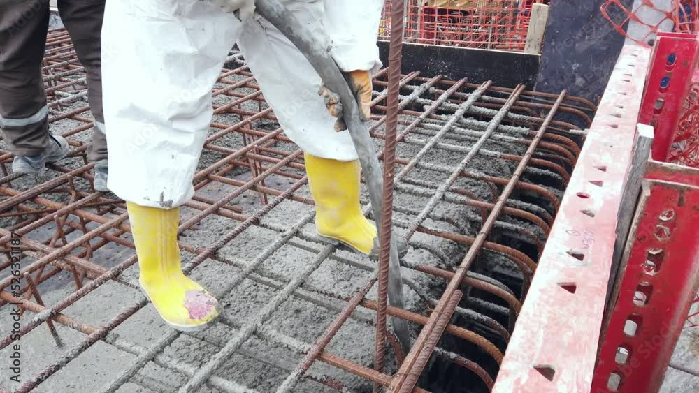 Construction worker dressed in protective workwear uses concrete ...