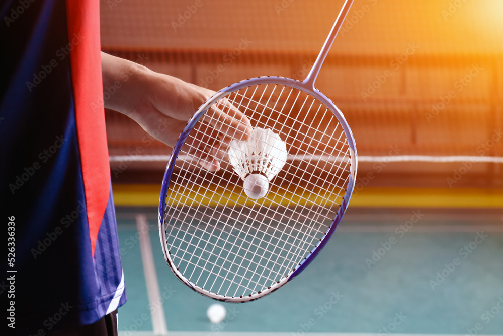 Badminton player holds racket and white cream shuttlecock in front of ...