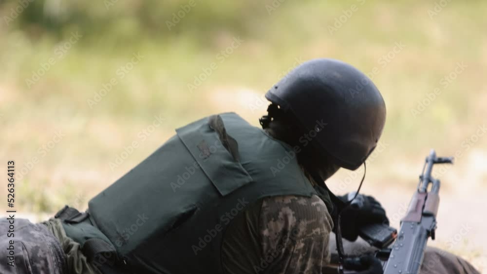 Armed military man unloading machine gun while lying with gun, soldier ...