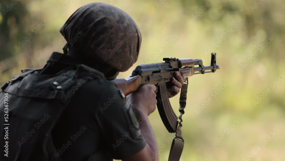 Military man in green uniform vest unloading gun with machine gun in ...