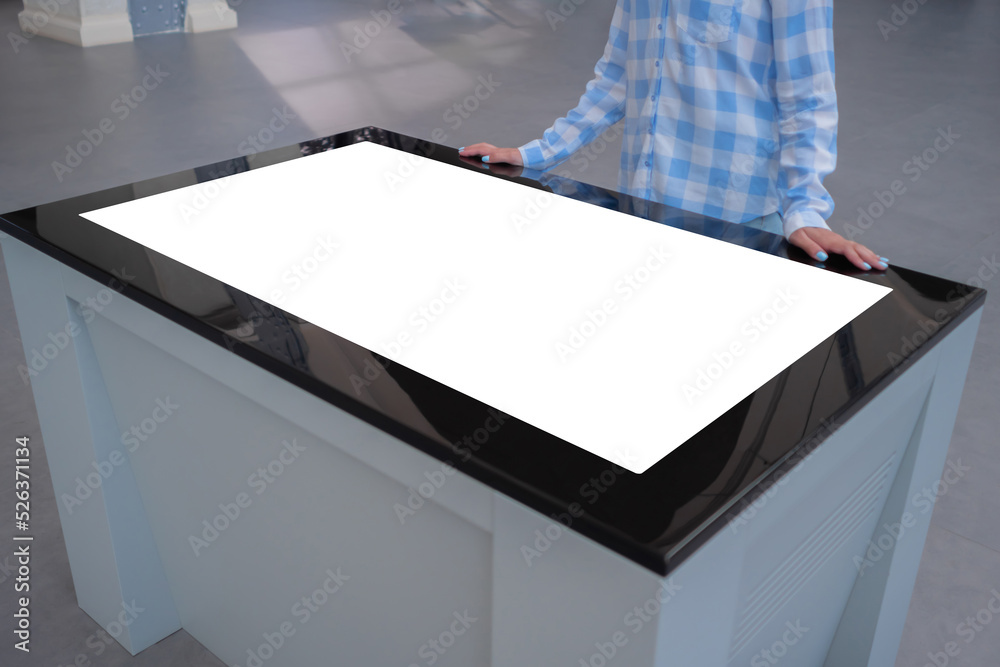 Woman in blue plaid shirt looking at blank interactive touchscreen ...