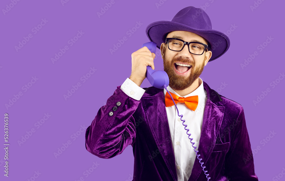 Smiling showman isolated on purple studio background talk on corded ...