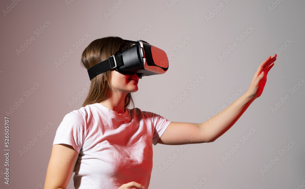 Excited brunette young woman in VR headset touching air during virtual ...