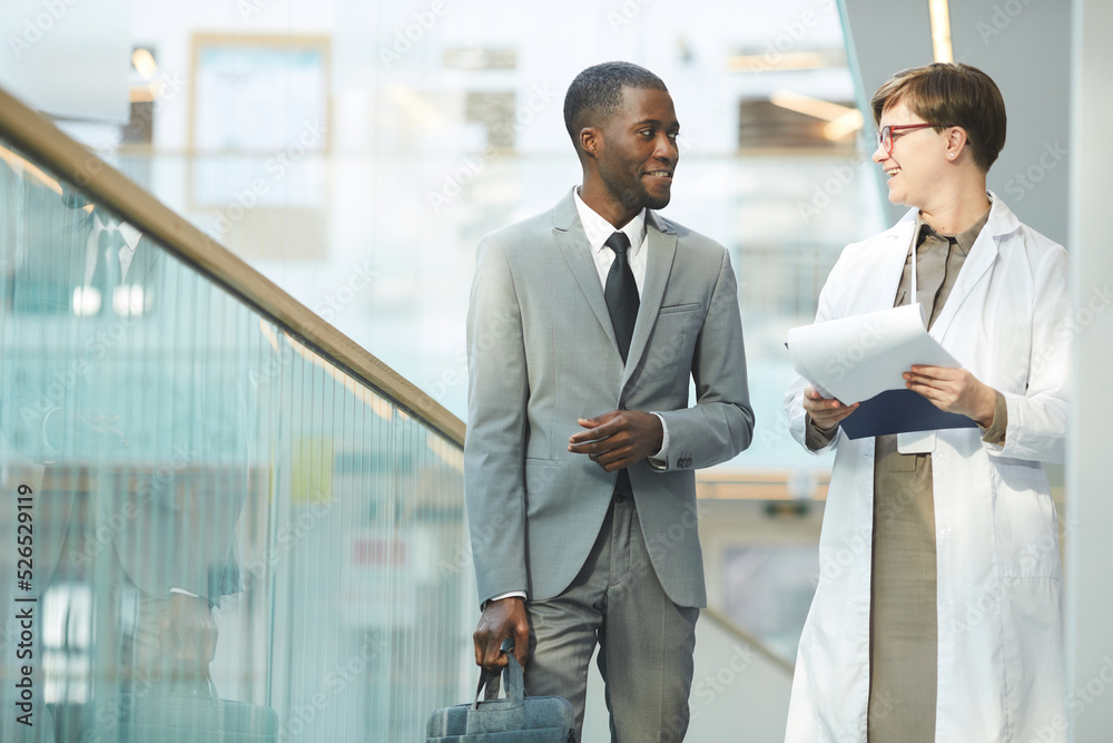 Portrait of smiling black businessman talking to female colleague while ...
