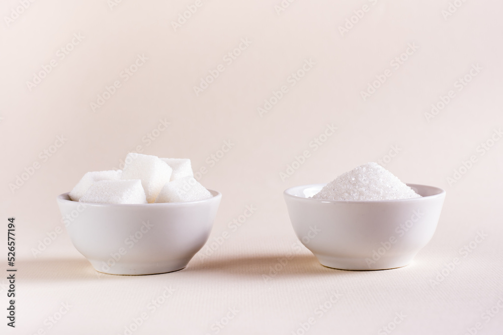 Sugar cubes and granulated sugar in bowls on a light background ...