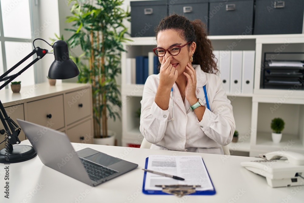 Young hispanic woman wearing doctor uniform and stethoscope smelling ...