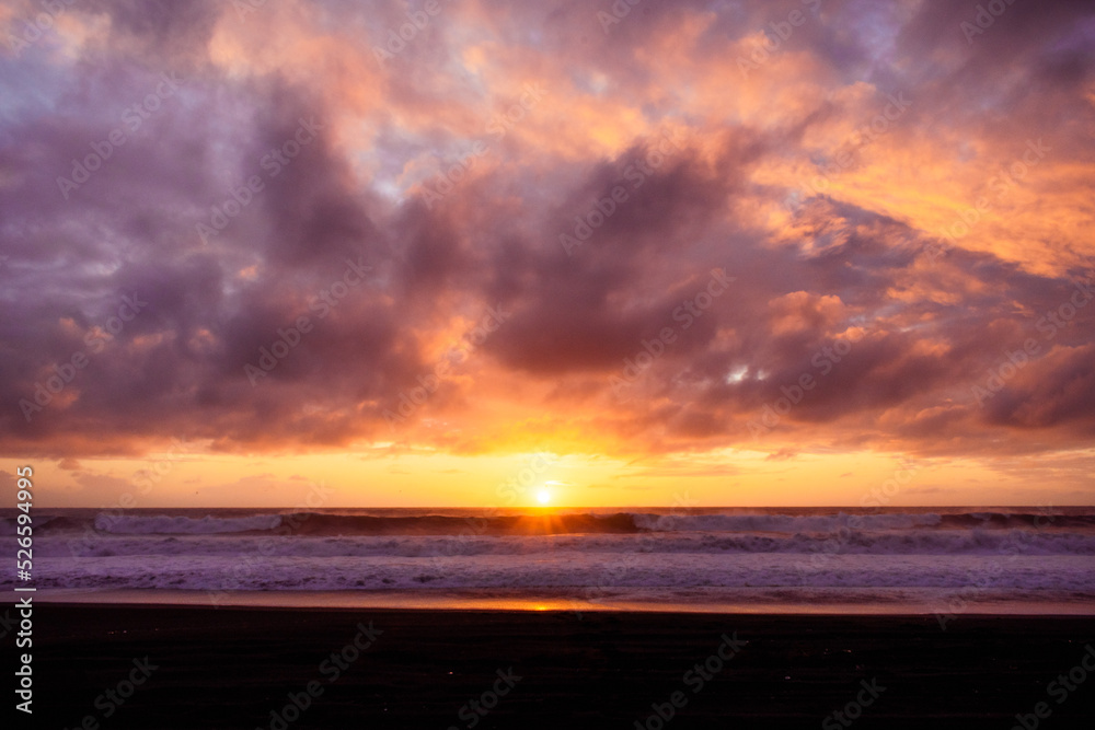 Paisaje de atardecer en la playa con ocaso en el mar y nubes iluminadas ...