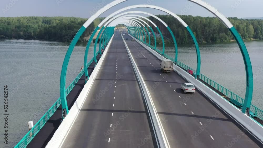 Flight under arches of new modern automobile bridge across river ...