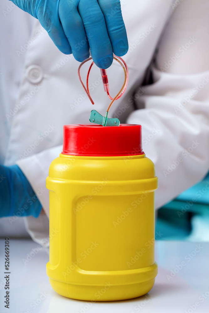 lab Technician depositing equipment from a blood draw in a Biohazard ...