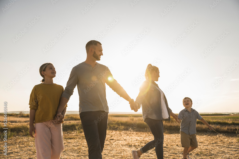 Confident family walking together holding hands at sunset Stock Photo ...