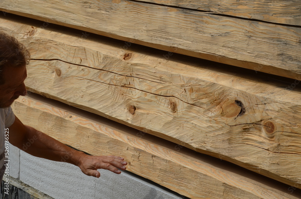 a carpenter built a log cabin with rough hewn beams. wood planing was ...