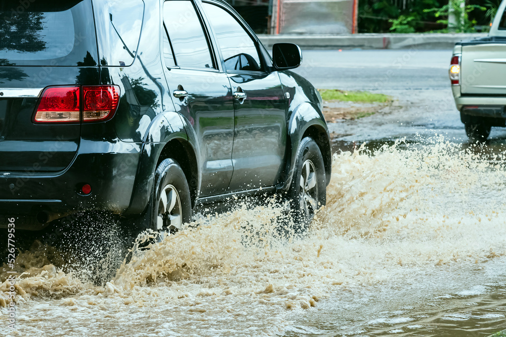Car passing through a flooded road. Driving car on flooded road during ...