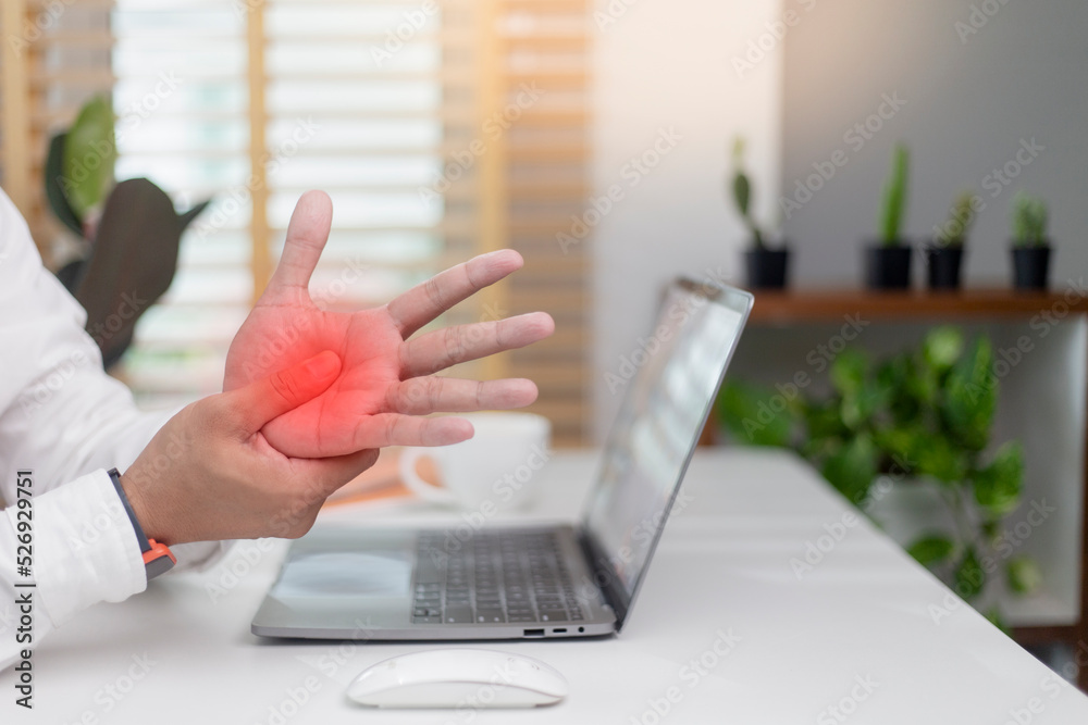 male worker sitting in the office with a laptop sore palm massage nerve ...
