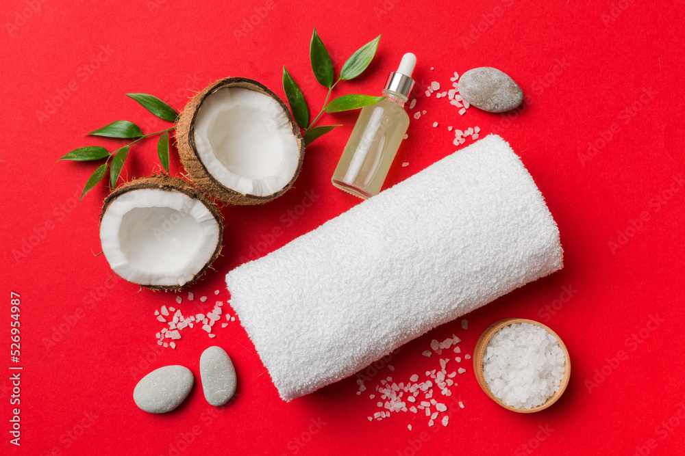Coconut with jars of coconut oil and cosmetic cream on colored ...