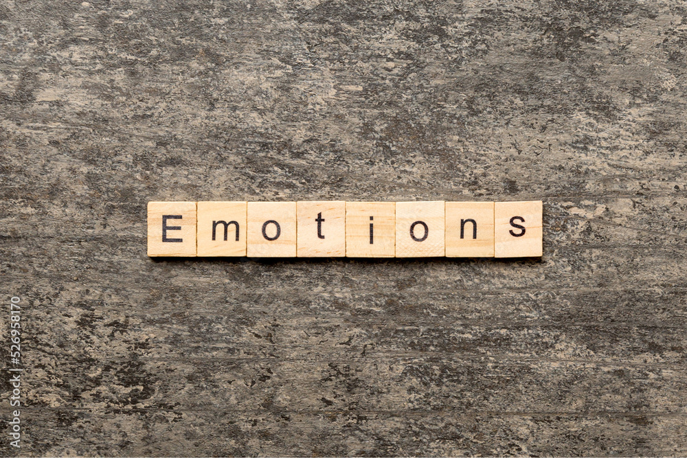 EMOTIONS word written on wood block. EMOTIONS text on cement table for ...