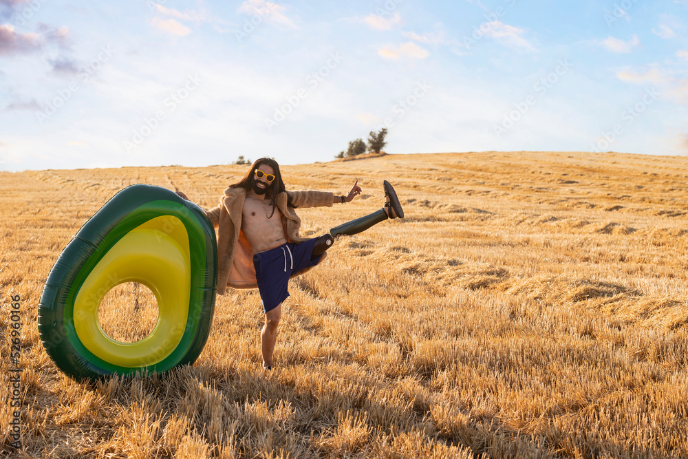 Happy hipster man with prosthetic leg balancing by inflatable ring at ...