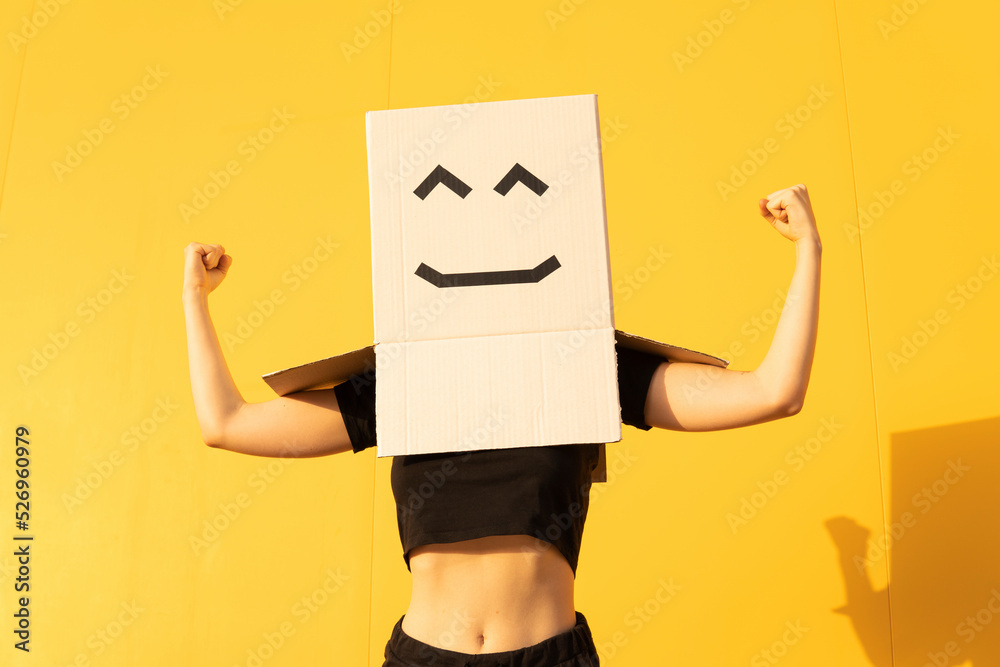 Woman wearing box with face flexing muscle standing in front of of ...