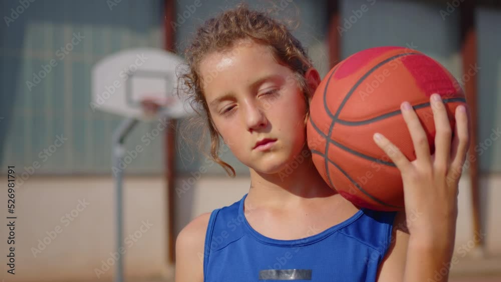 Boy standing on a basketball court and holding a basketball under his ...