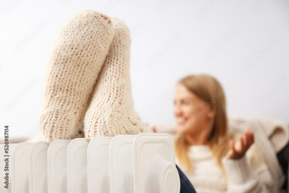 Heating season, woman warms her legs with heater Stock Photo | Adobe Stock