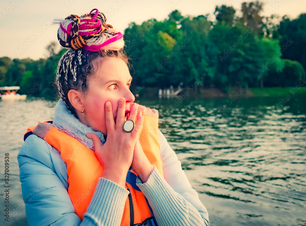 Middle aged woman with fancy hair wearing nautical lifejacket scared ...