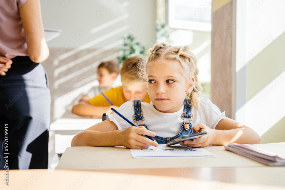 Little girl primary school girl student with two braids in classroom ...
