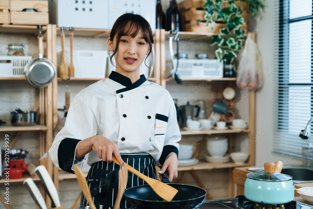 portrait of a female chef in uniform is looking at the camera while ...