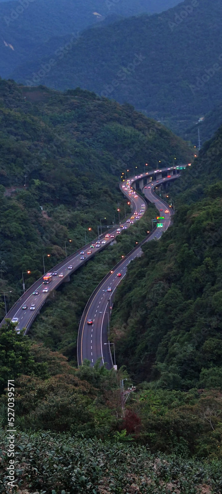 curved highway through the green rice fields with houses scattered ...