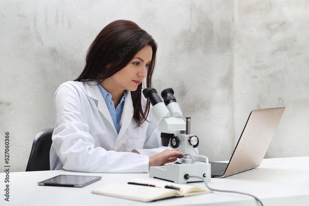 a woman in a lab coat looking through a microscope, portrait of a ...