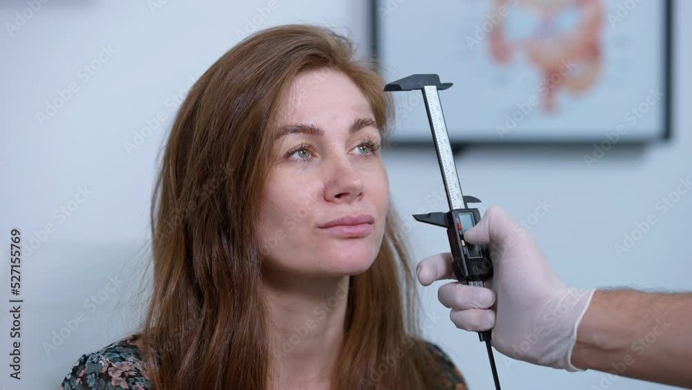 Close-up of positive Caucasian woman looking at unrecognizable doctor ...