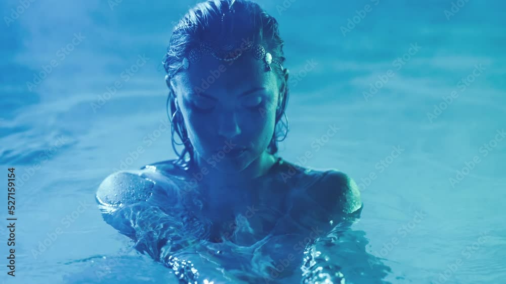 Beautiful wet woman posing in pool water under neon color light. Party ...