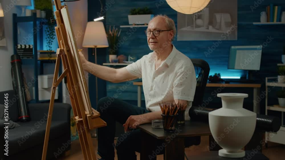 Portrait of retired man drawing professional artwork on canvas, using ...