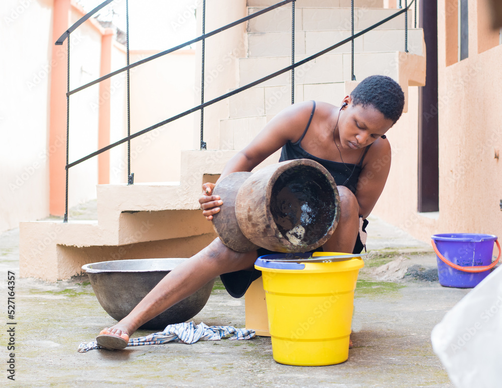 An African young girl, lady or woman from Nigeria doing house chores ...
