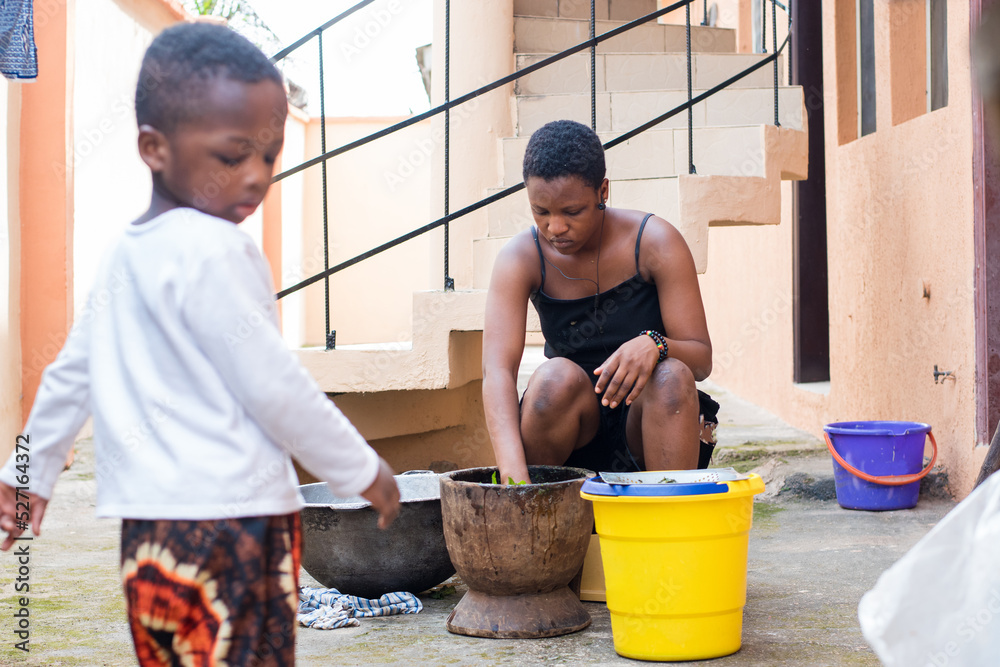 An African young girl, lady or woman from Nigeria doing house chores ...
